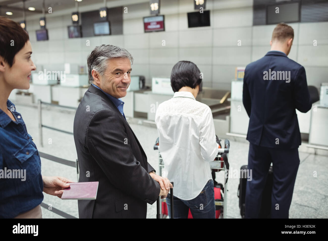 Passengers waiting in queue at a check-in counter with luggage Stock Photo - Alamy
