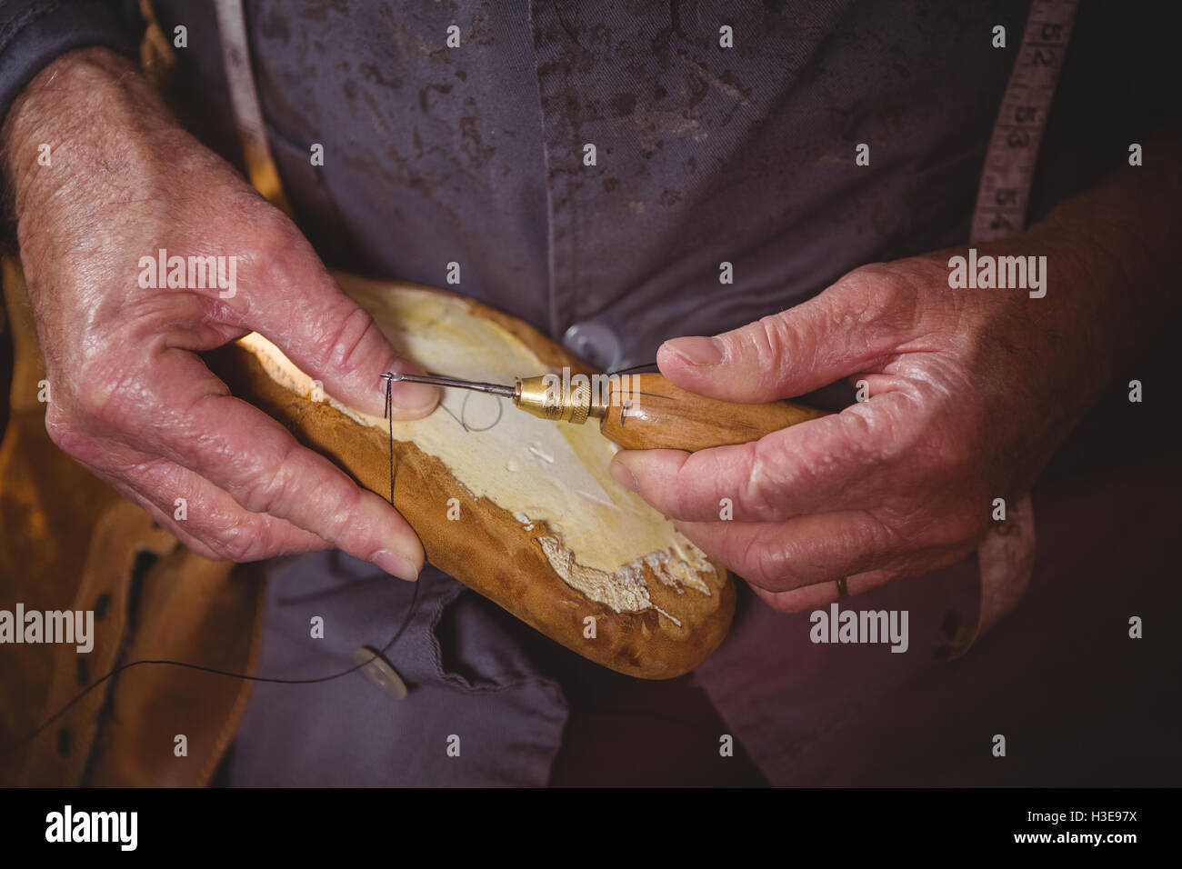 Shoemaker stitching shoe sole with needle Stock Photo - Alamy