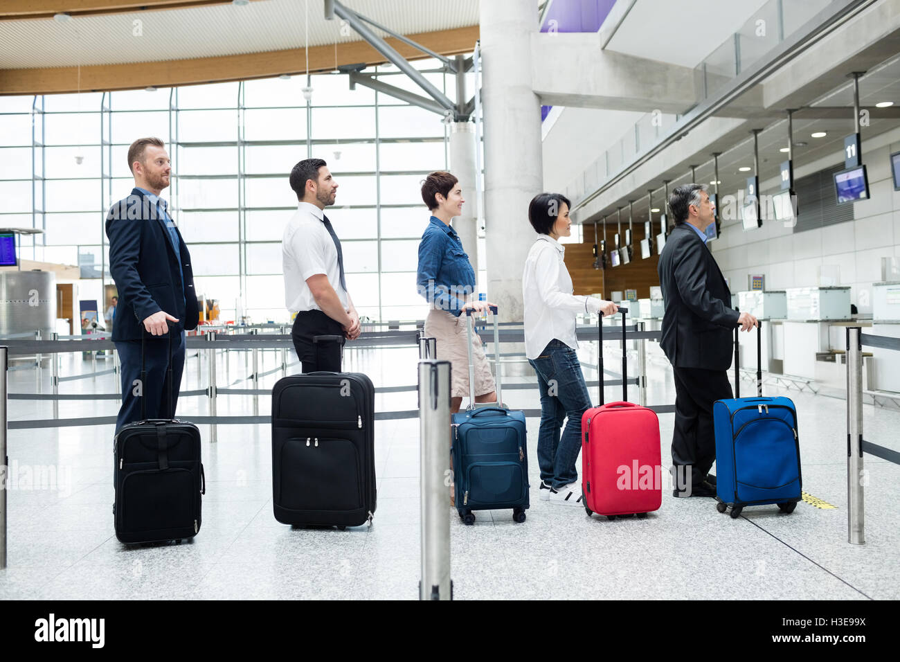 Passengers waiting in queue at a check-in counter with luggage Stock ...