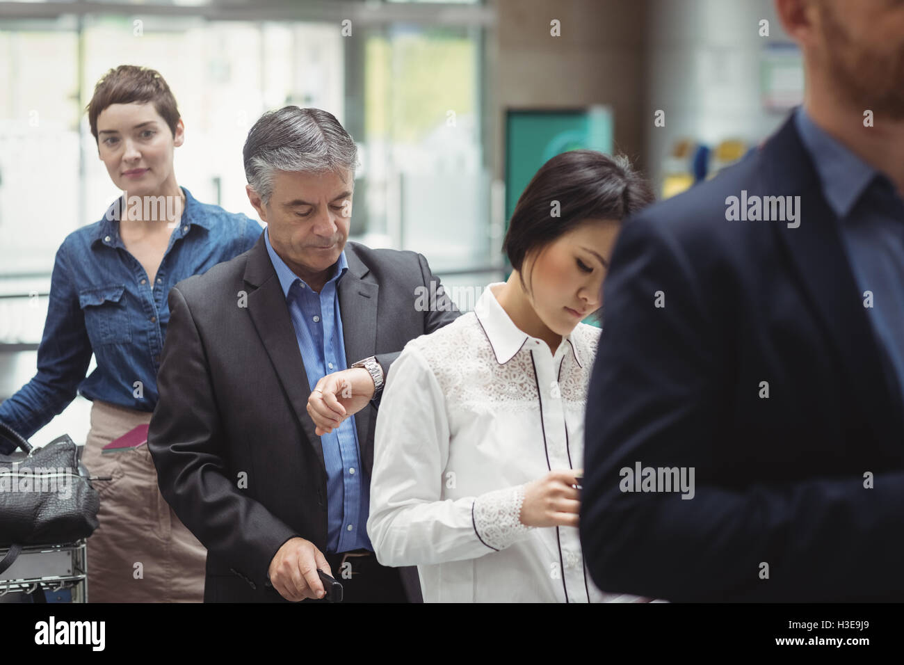 Passengers waiting in queue at a check-in counter with luggage Stock Photo - Alamy