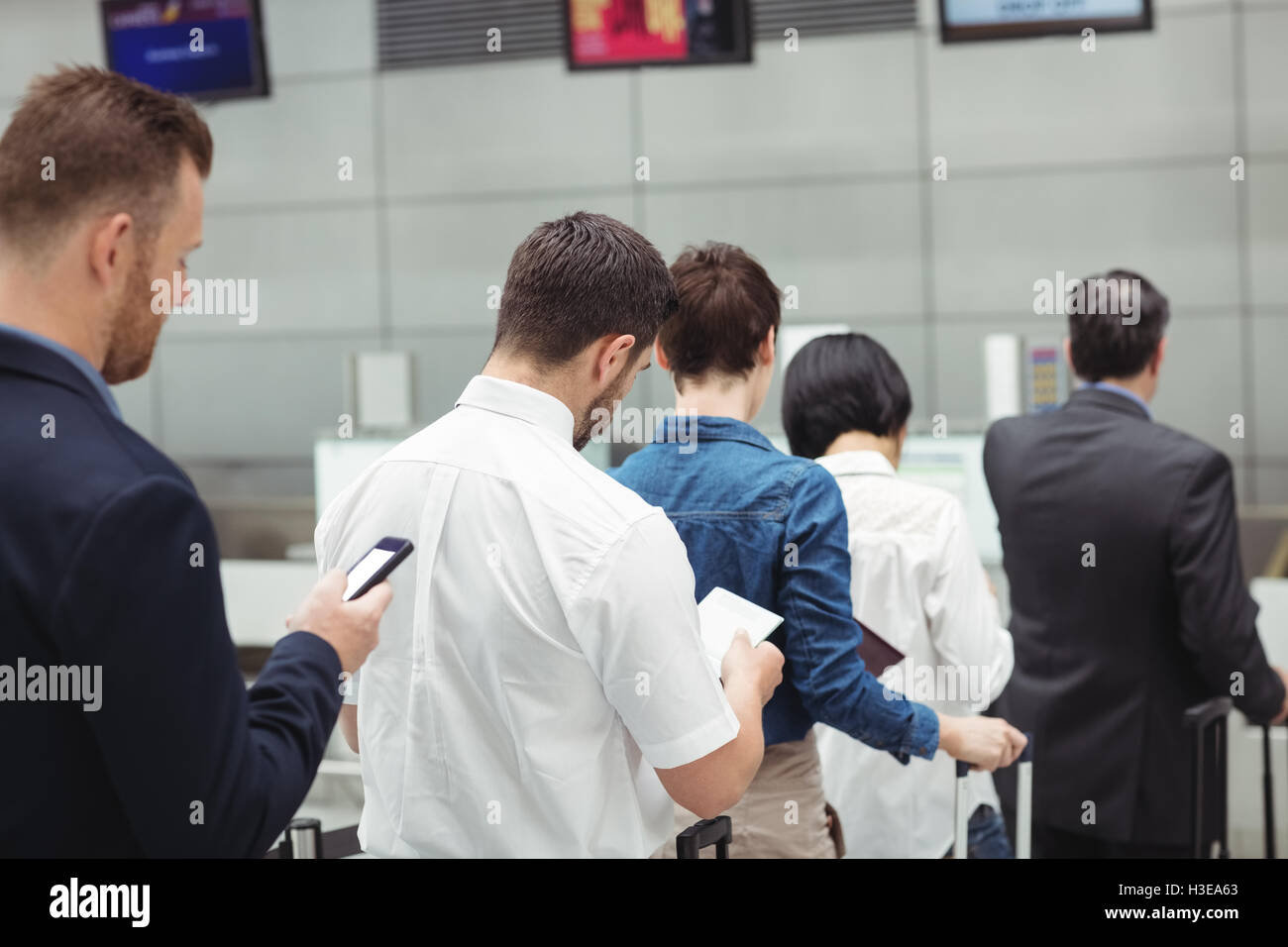 Passengers waiting in queue at a check-in counter with luggage Stock ...