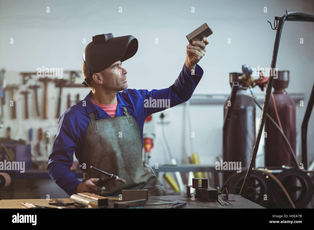 Male welder examining a piece of metal Stock Photo - Alamy
