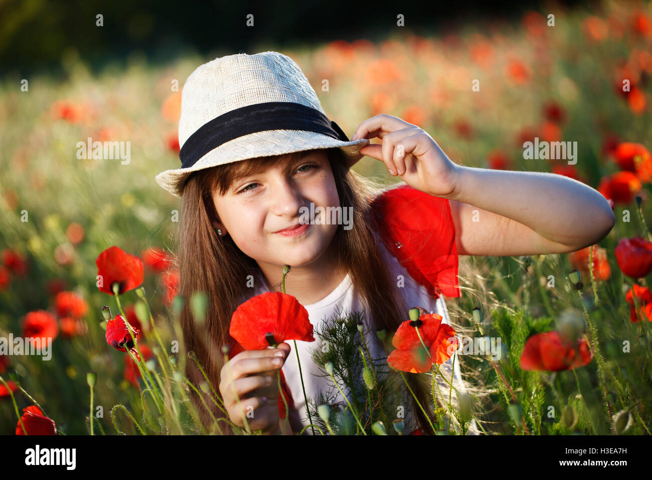 Portrait of a cute little girl in the meadow with poppies Stock Photo ...