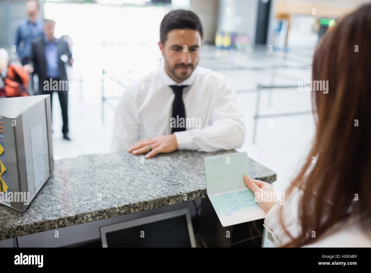 Airline check-in attendant checking passport of passenger Stock Photo ...