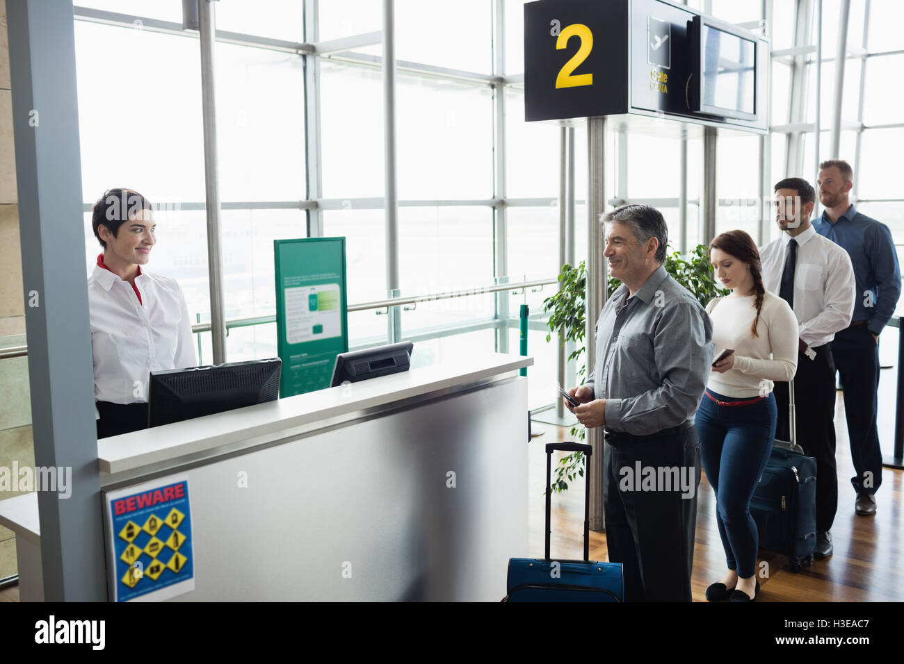 Passengers waiting in queue at check-in counter Stock Photo - Alamy