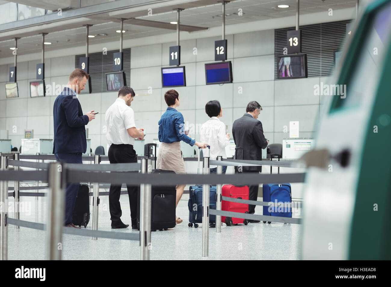 Passengers waiting in queue at a check-in counter with luggage Stock ...