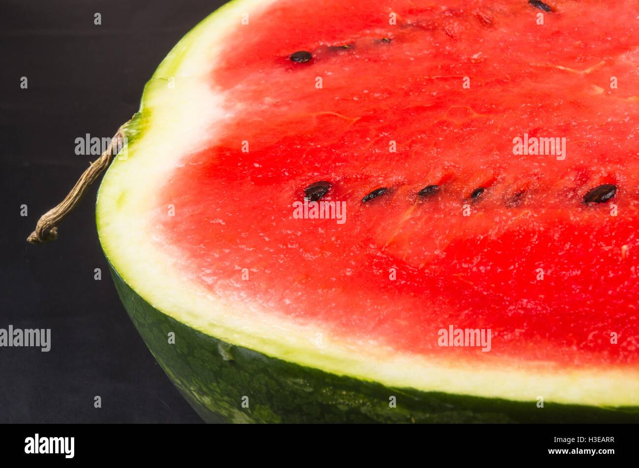 half of ripe watermelon on a black background Stock Photo - Alamy