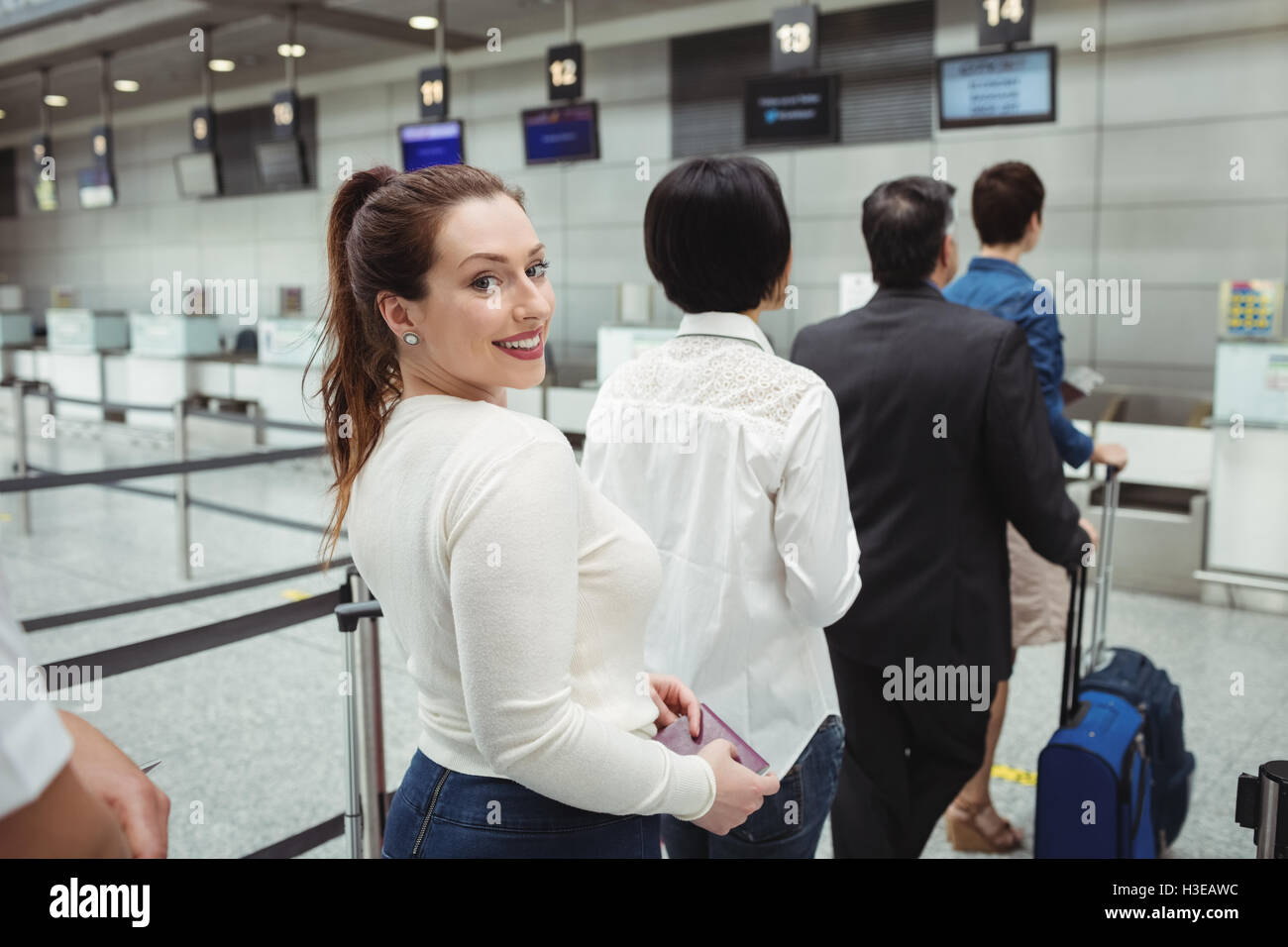 Passengers waiting in queue at a check-in counter with luggage Stock Photo - Alamy