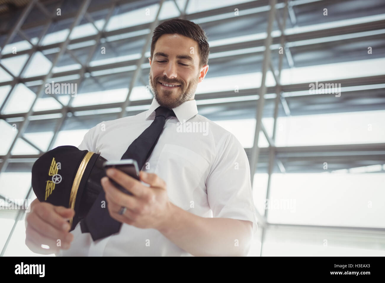 Pilot using mobile phone in waiting area Stock Photo - Alamy