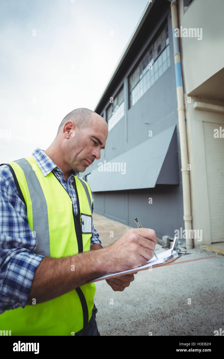 Construction worker writing on a clipboard Stock Photo - Alamy