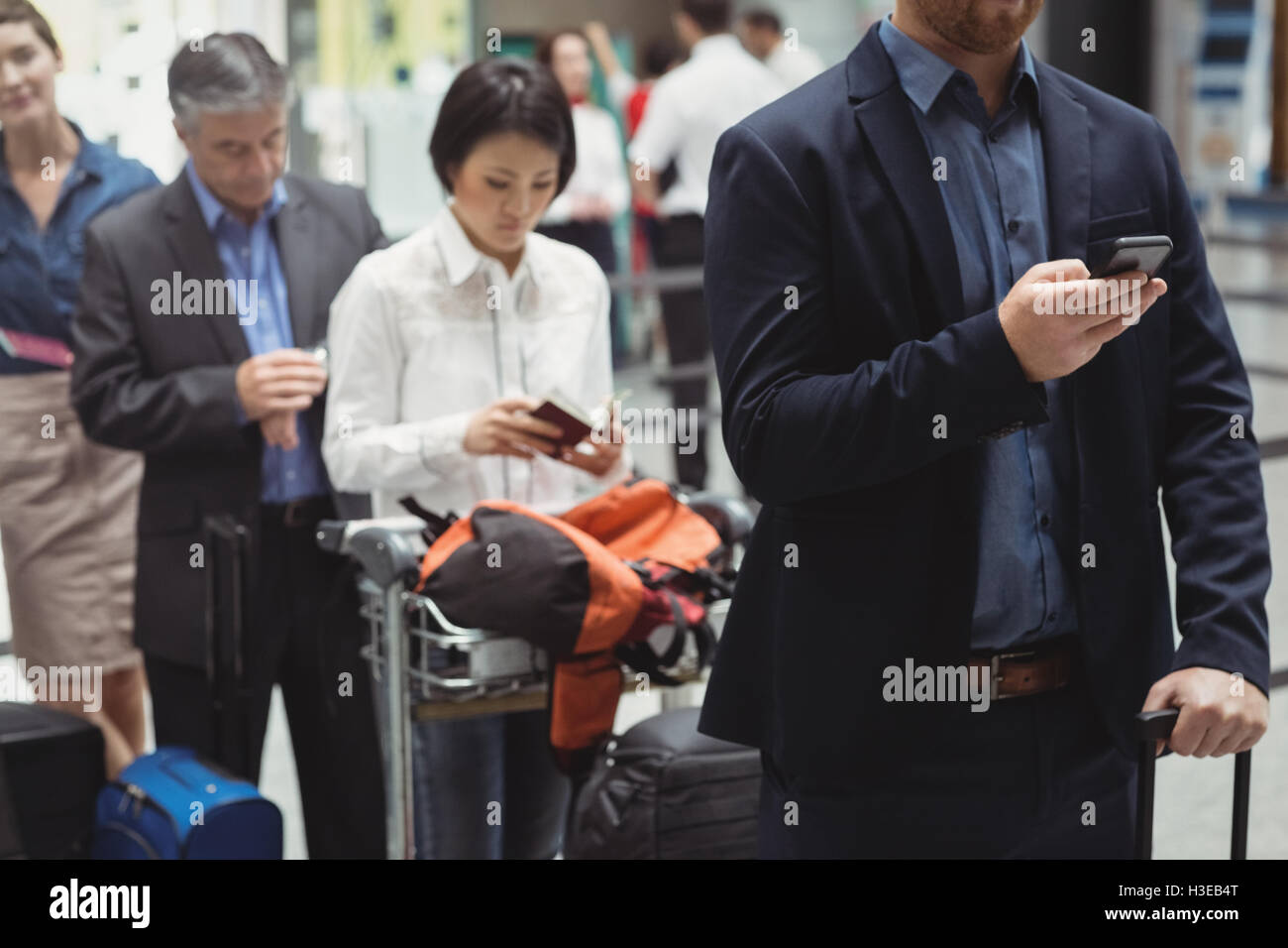 Passengers waiting in queue at a check-in counter with luggage Stock Photo - Alamy