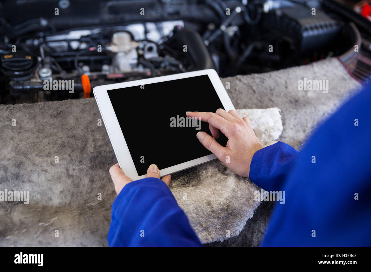 Mechanic using a digital tablet while servicing car engine Stock Photo ...