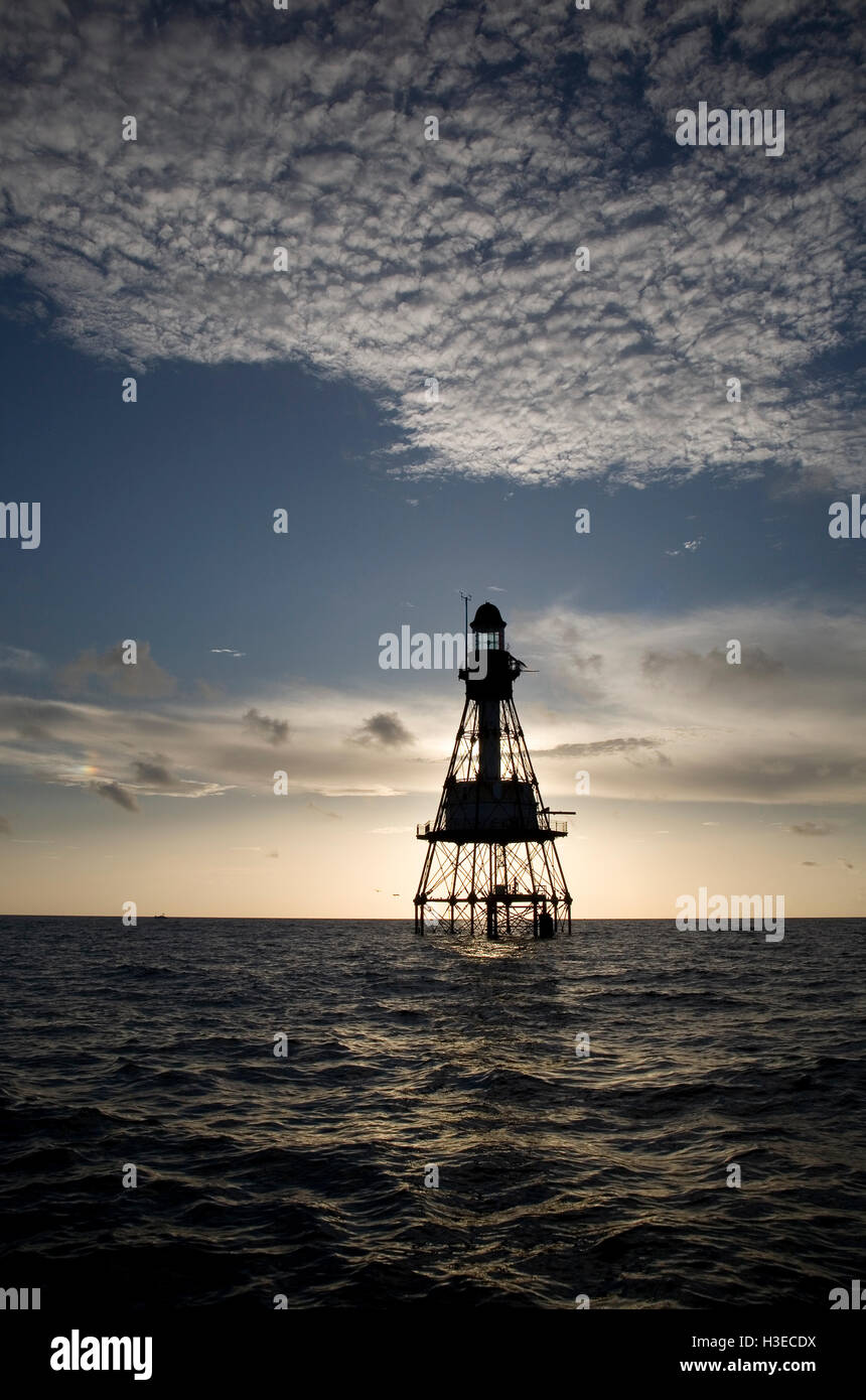 Fowey Rocks Lighthouse is silhouetted against the rising sun with ...