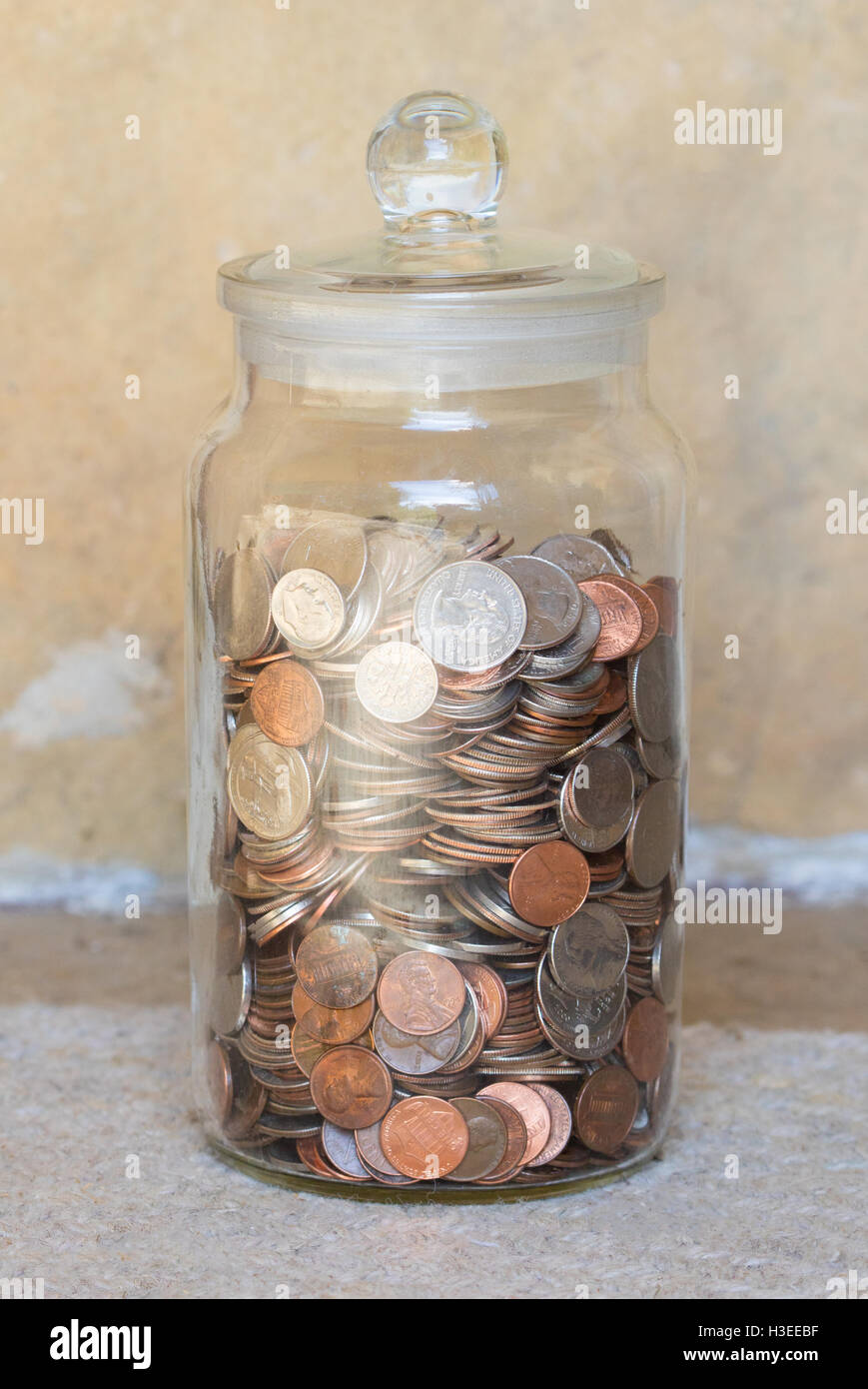 A collection of loose change in a glass jar with a lid Stock Photo - Alamy