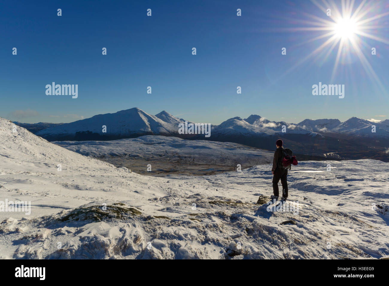Female hill walker looking towards the snow covered Munros from Ben ...