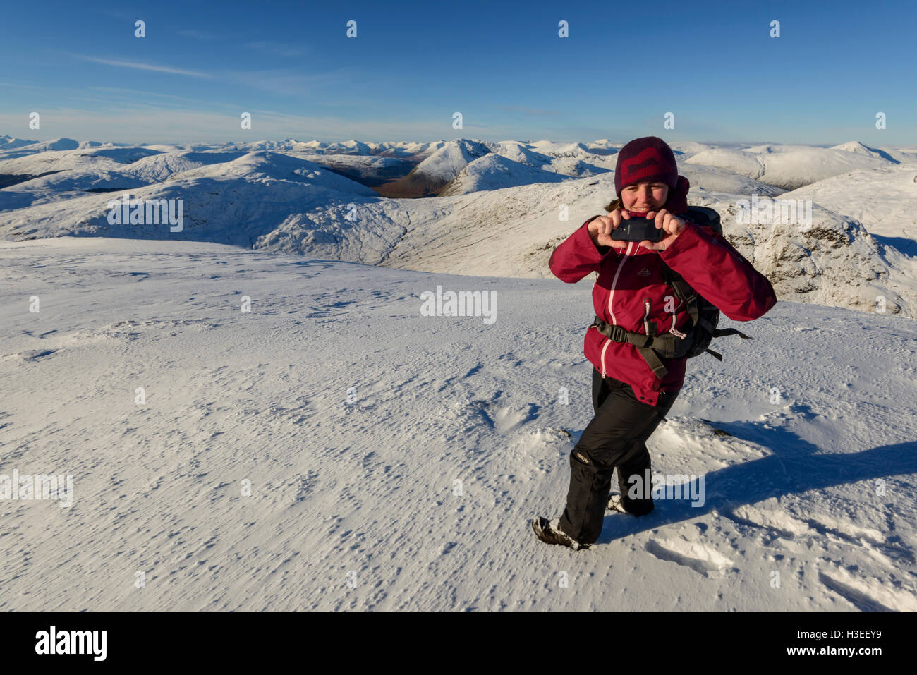 Female hill walker taking mobile phone photographs from the summit of ...