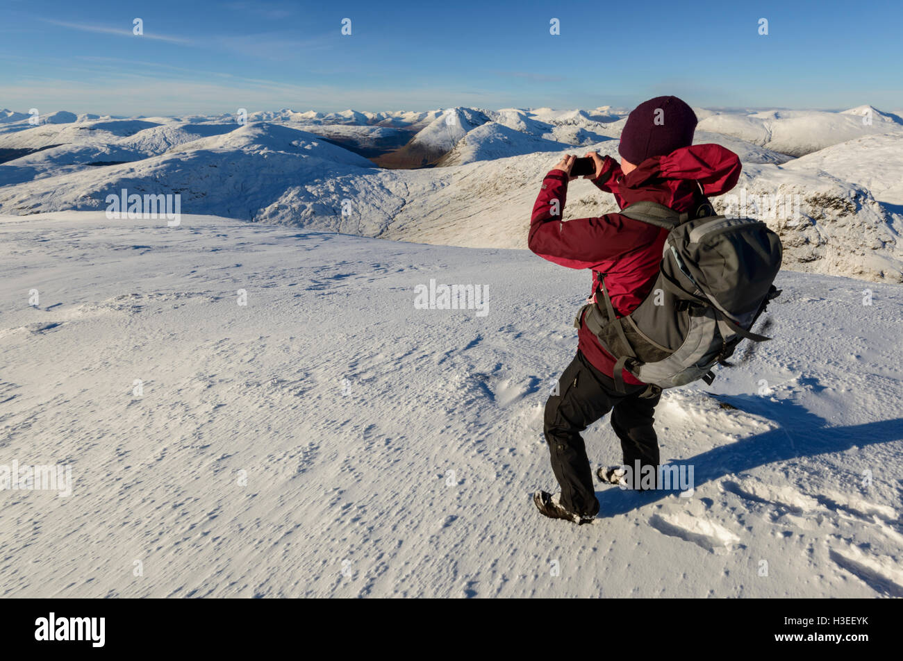 Female hill walker taking mobile phone photographs from the summit of ...