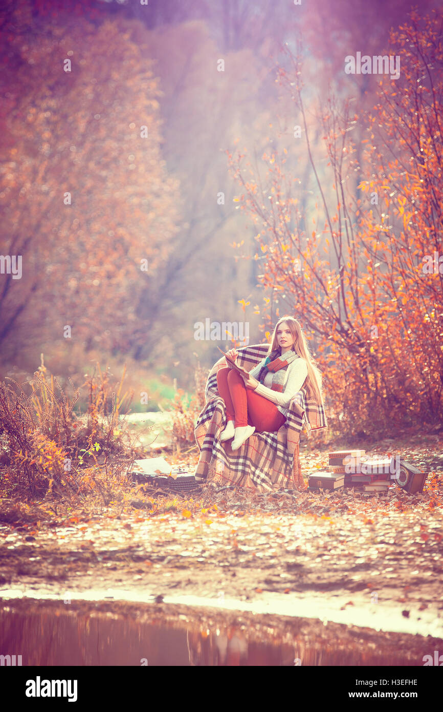 Beautyful poetess is wrighting a poem on a chair in yellowed forest ...