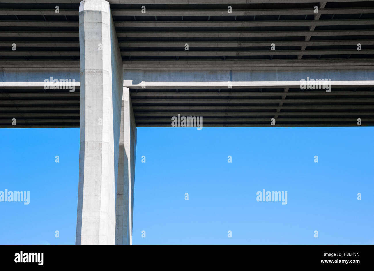 Underside of large concrete highway bridge and pylons at right angle ...