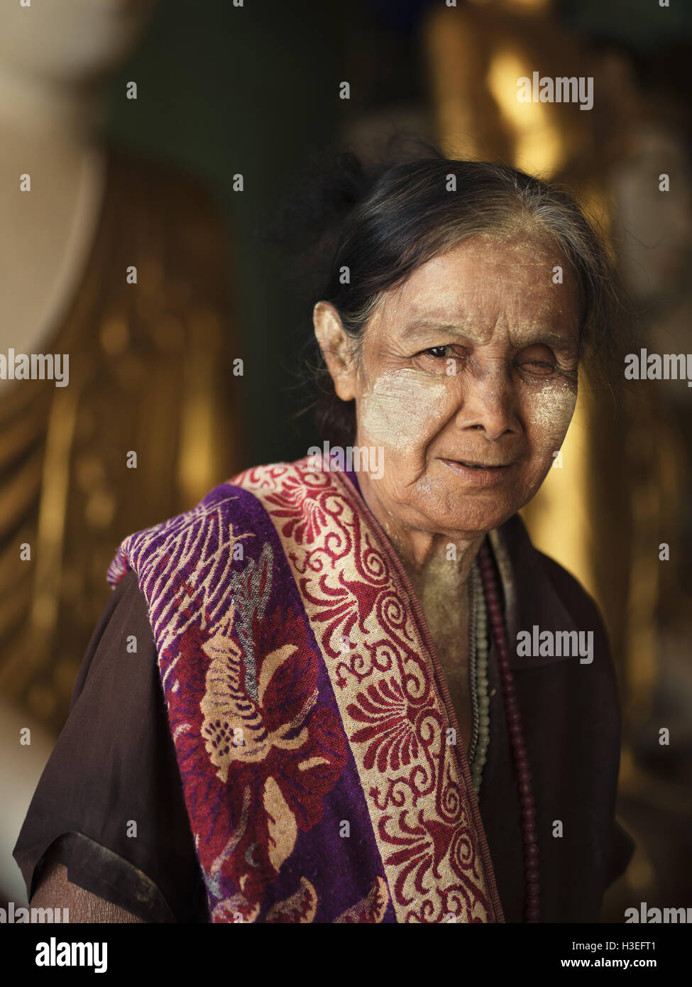 A Myanmarese woman displays thanaka, which is the yellow paste on her ...