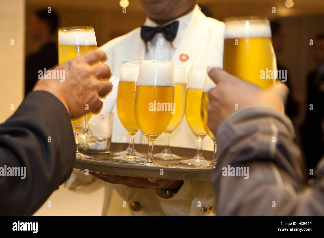 Happy hour, waiter serving beer to business people at office party ...
