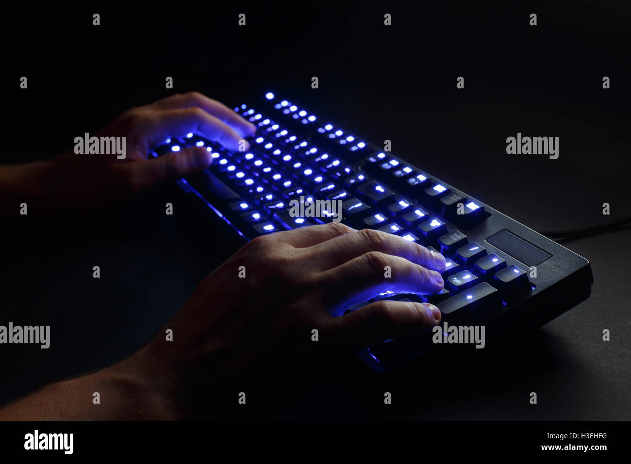 illuminated keyboard. male hands typing on a computer. hacker or ...
