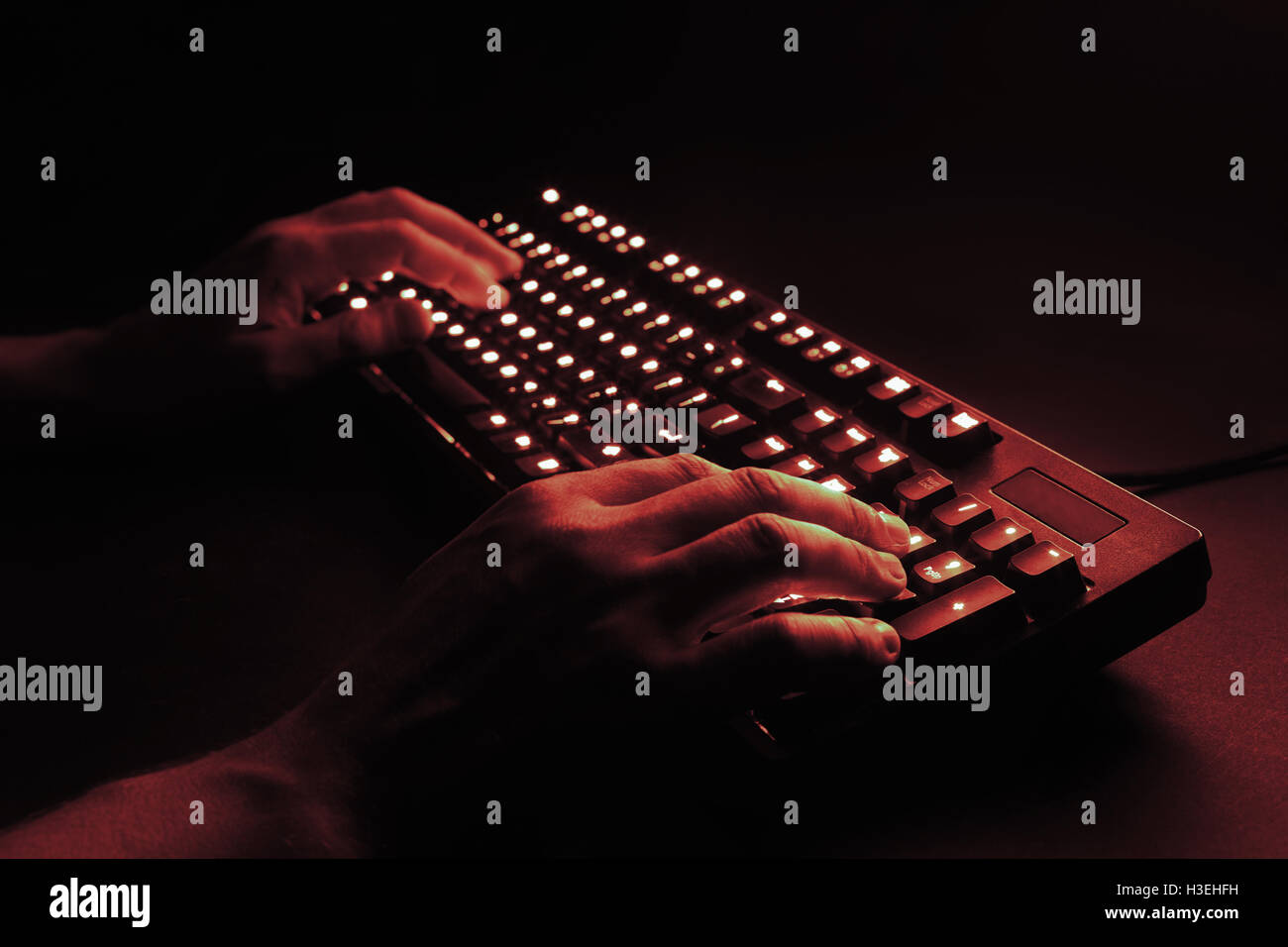 illuminated keyboard. male hands typing on a computer. hacker or ...
