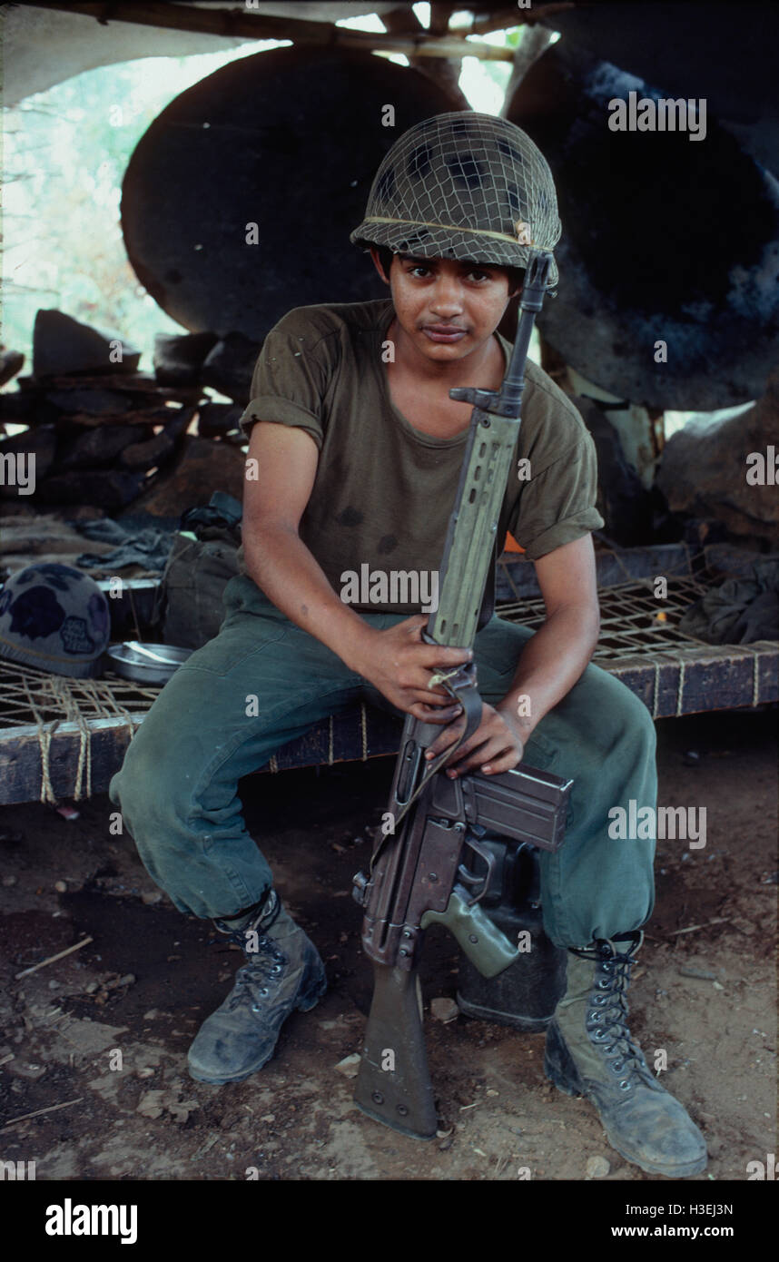 A government soldier sits on a bed about to clean his rifle while off ...