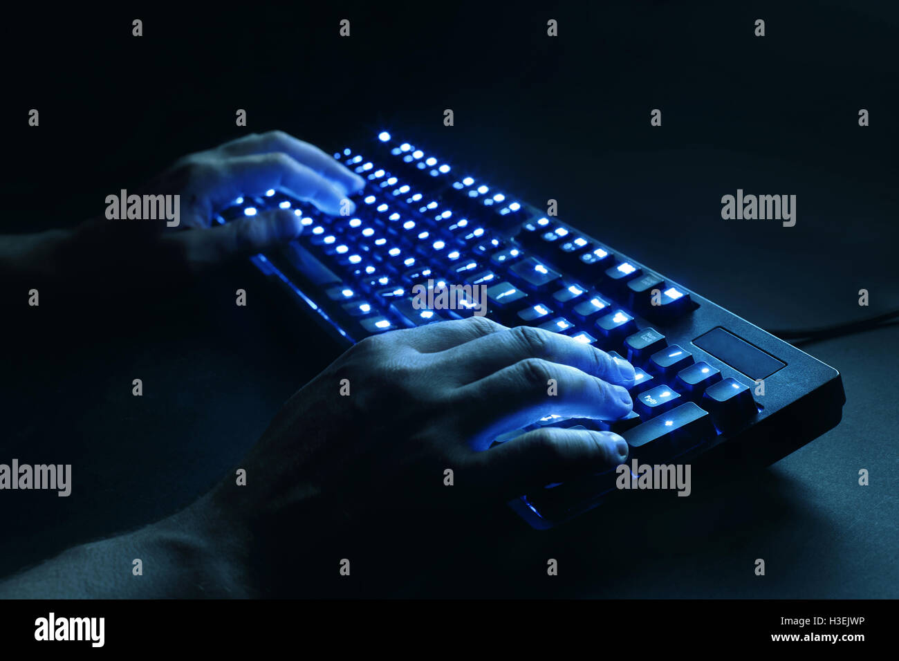 illuminated keyboard. male hands typing on a computer. hacker or ...