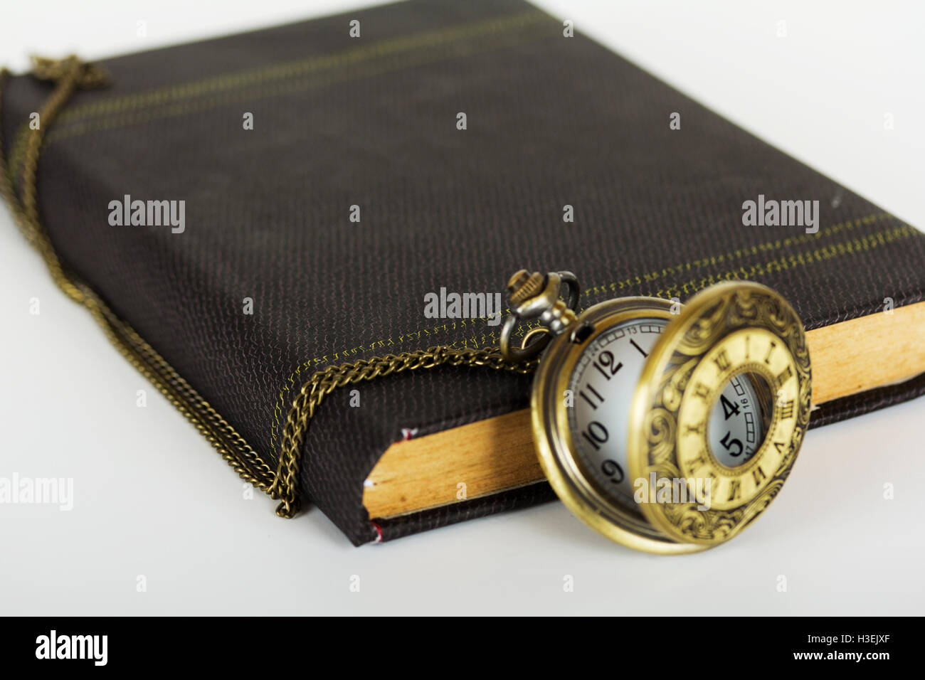 Pocket watch and book against a light coloured background Stock Photo ...