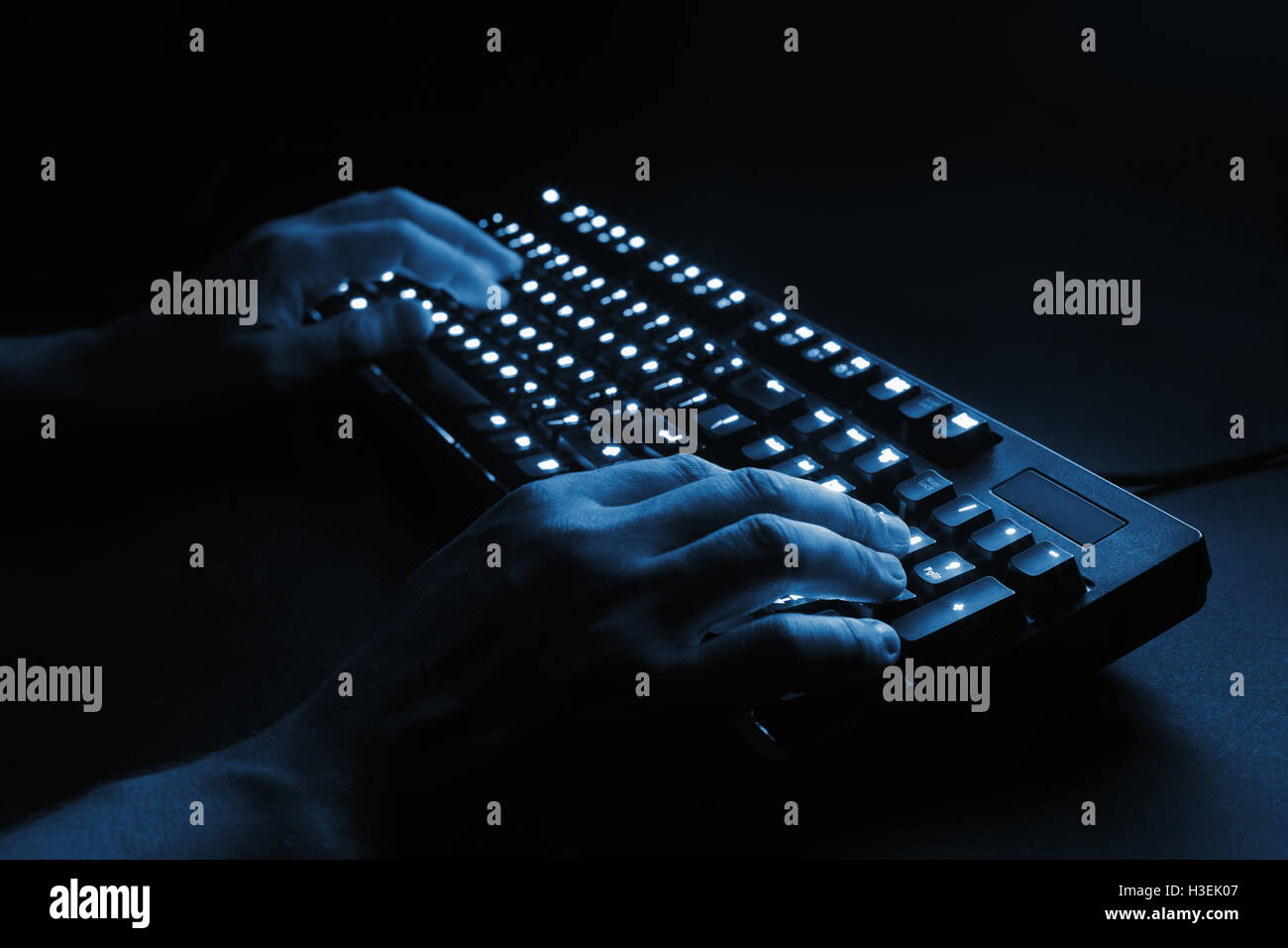 illuminated keyboard. male hands typing on a computer. hacker or ...