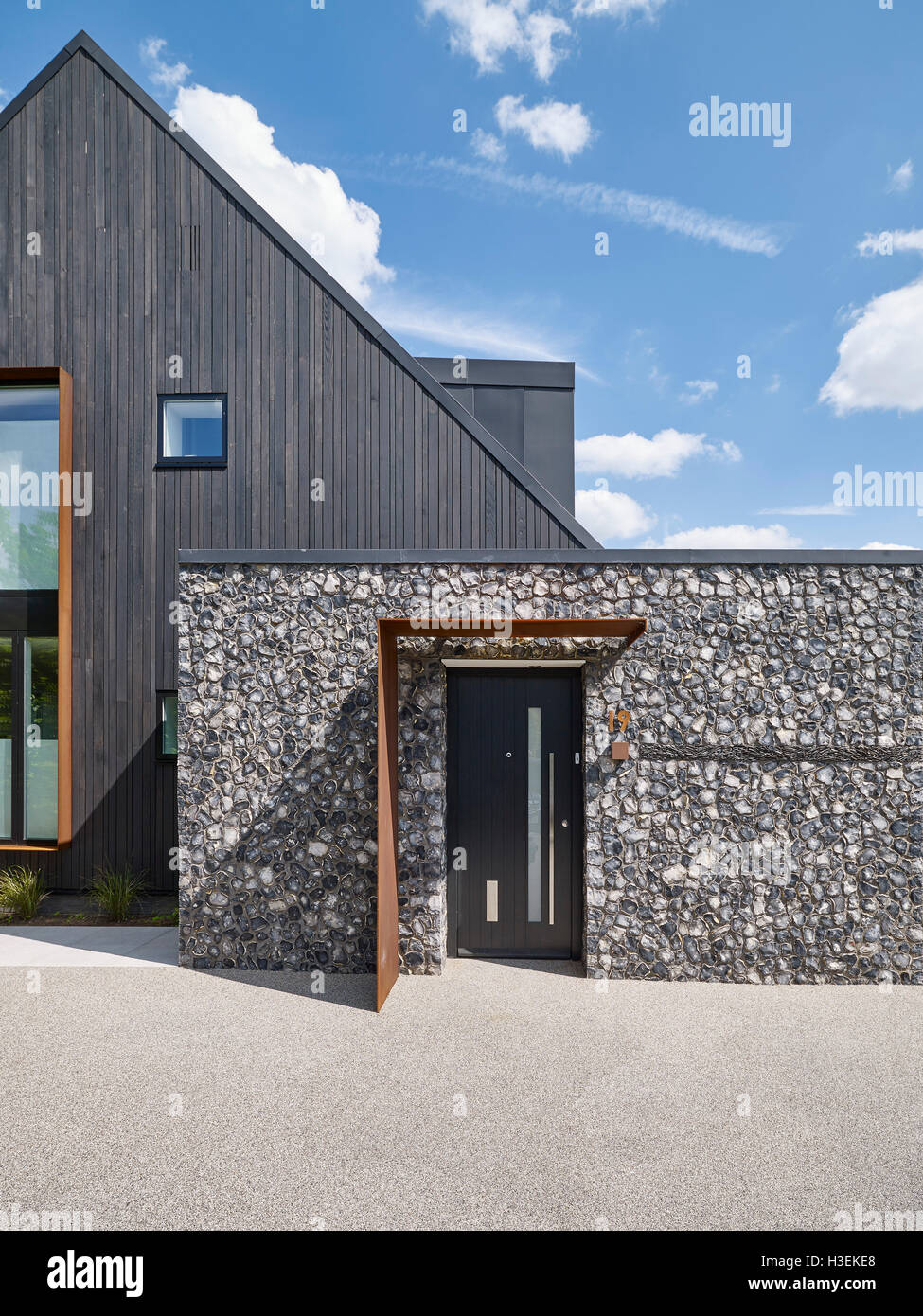 Entrance to the house. Front elevation with flint and rusted corten ...