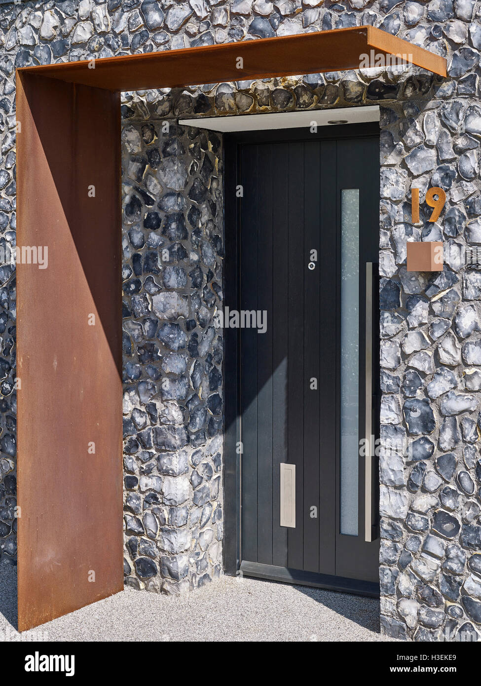 Entrance to the house. Front elevation with flint and rusted corten ...