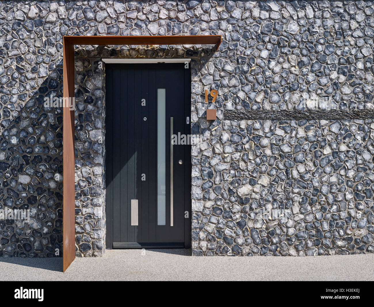 Entrance to the house. Front elevation with flint and rusted corten ...