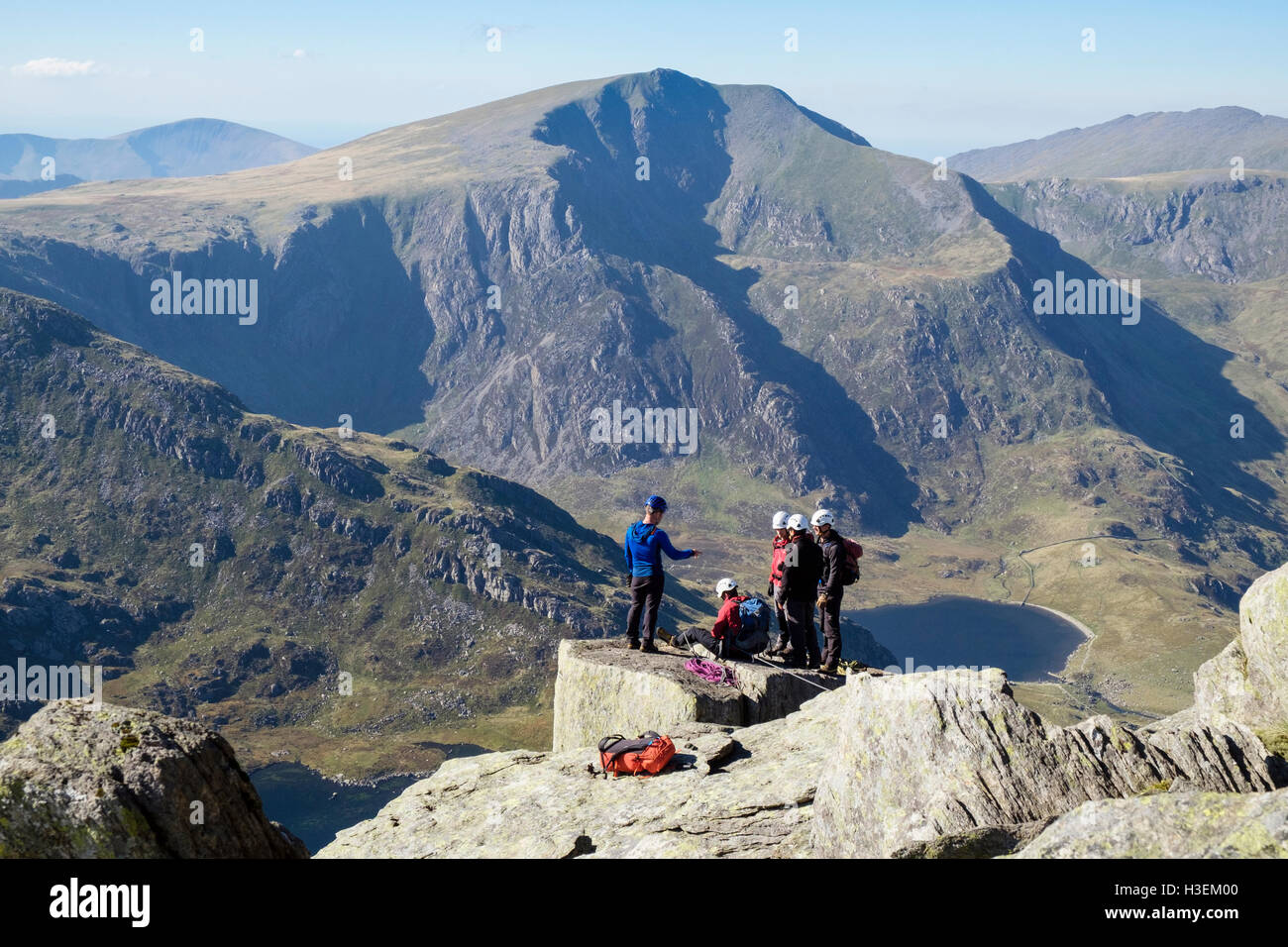 Men learning to rock climb on a crag on Tryfan with view to Y Garn as ...