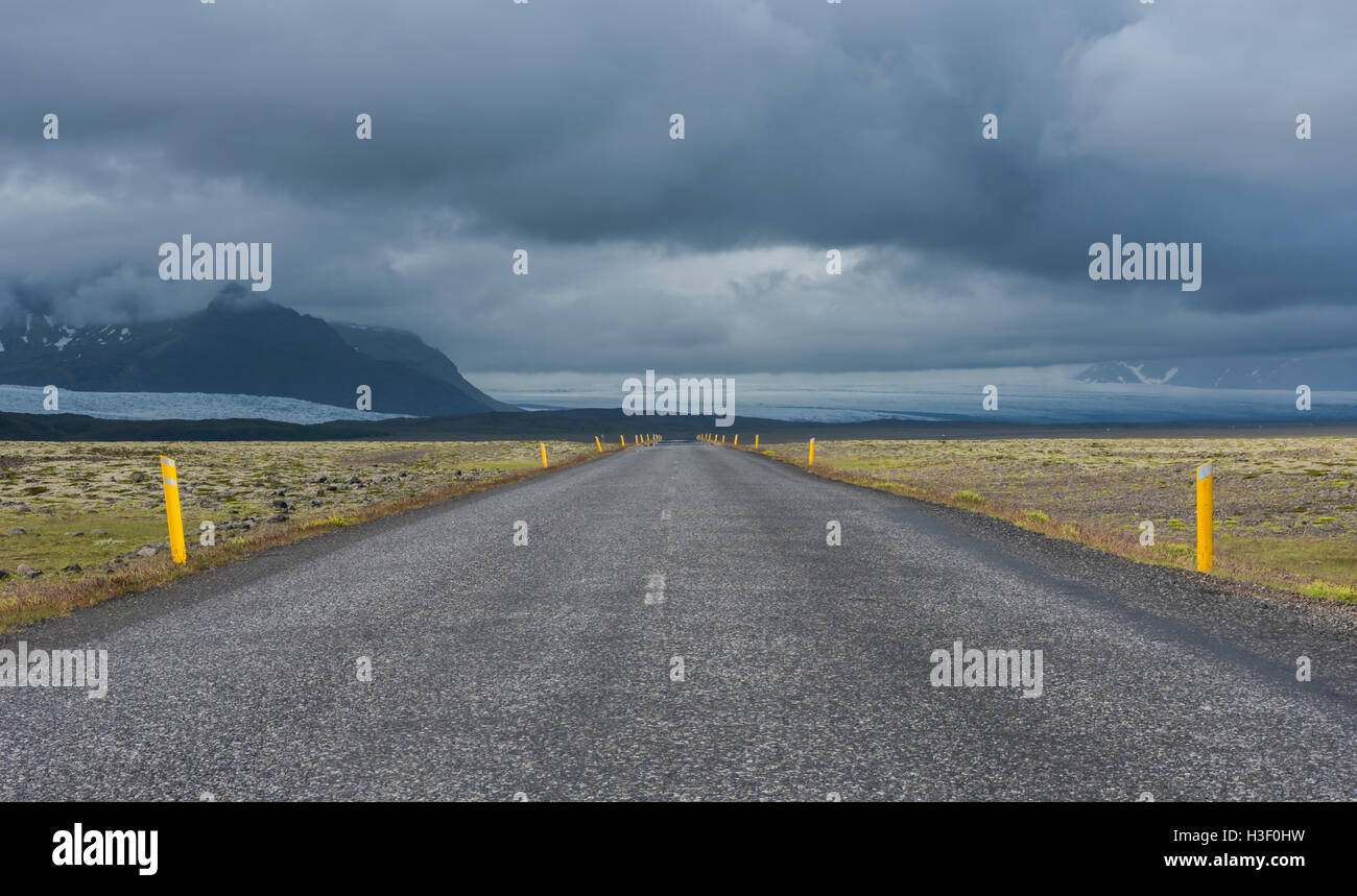 Long strait road on Iceland wit dark clouds and mountains on Iceland ...