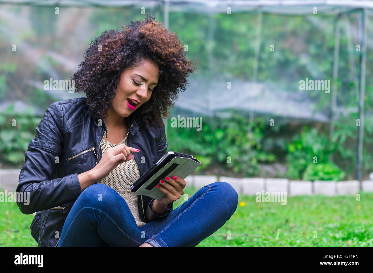 exotic beautiful young girl sitting in the garden using tablet Stock ...