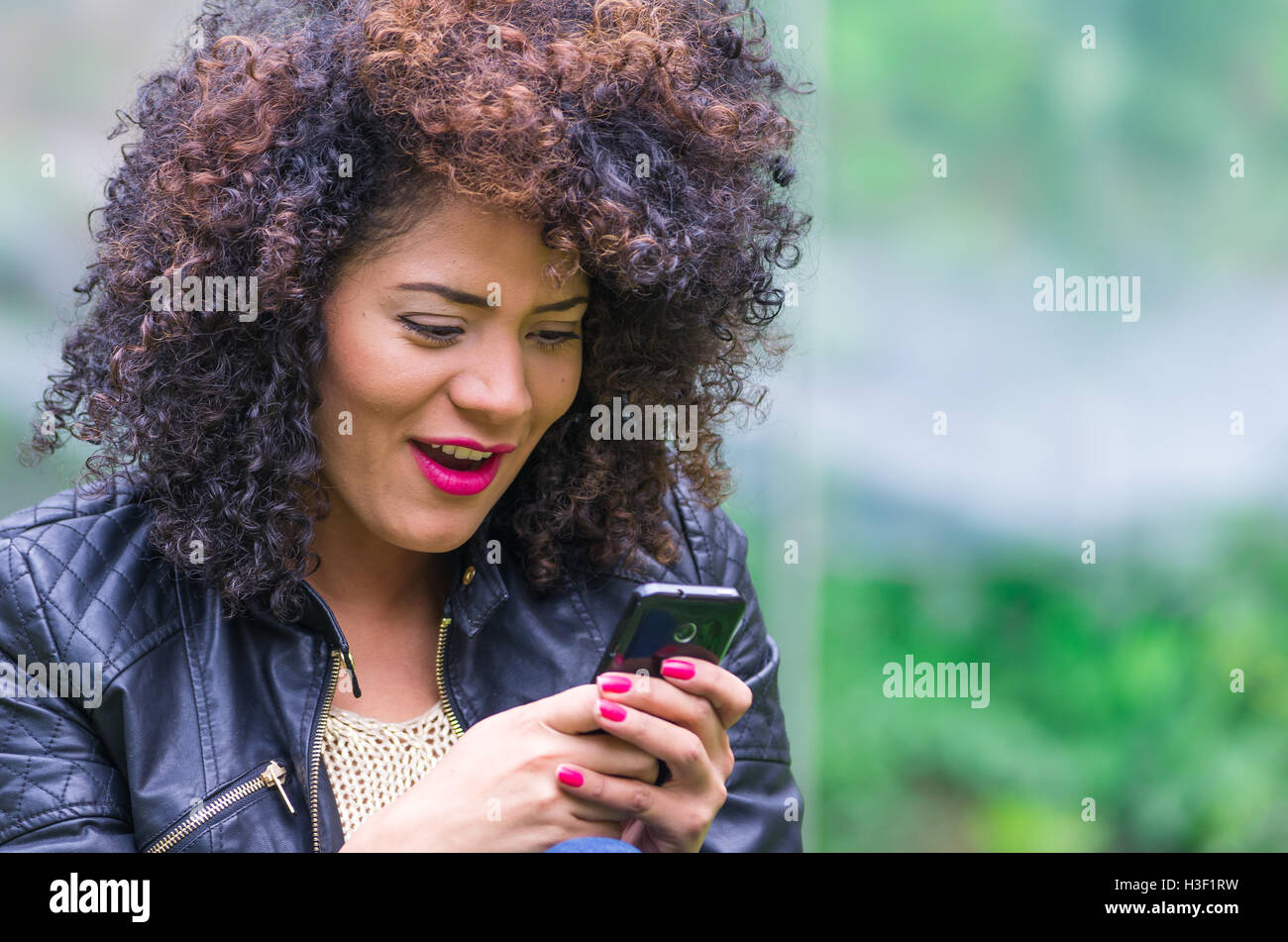 exotic beautiful young girl using cell phone sitting in the garden ...