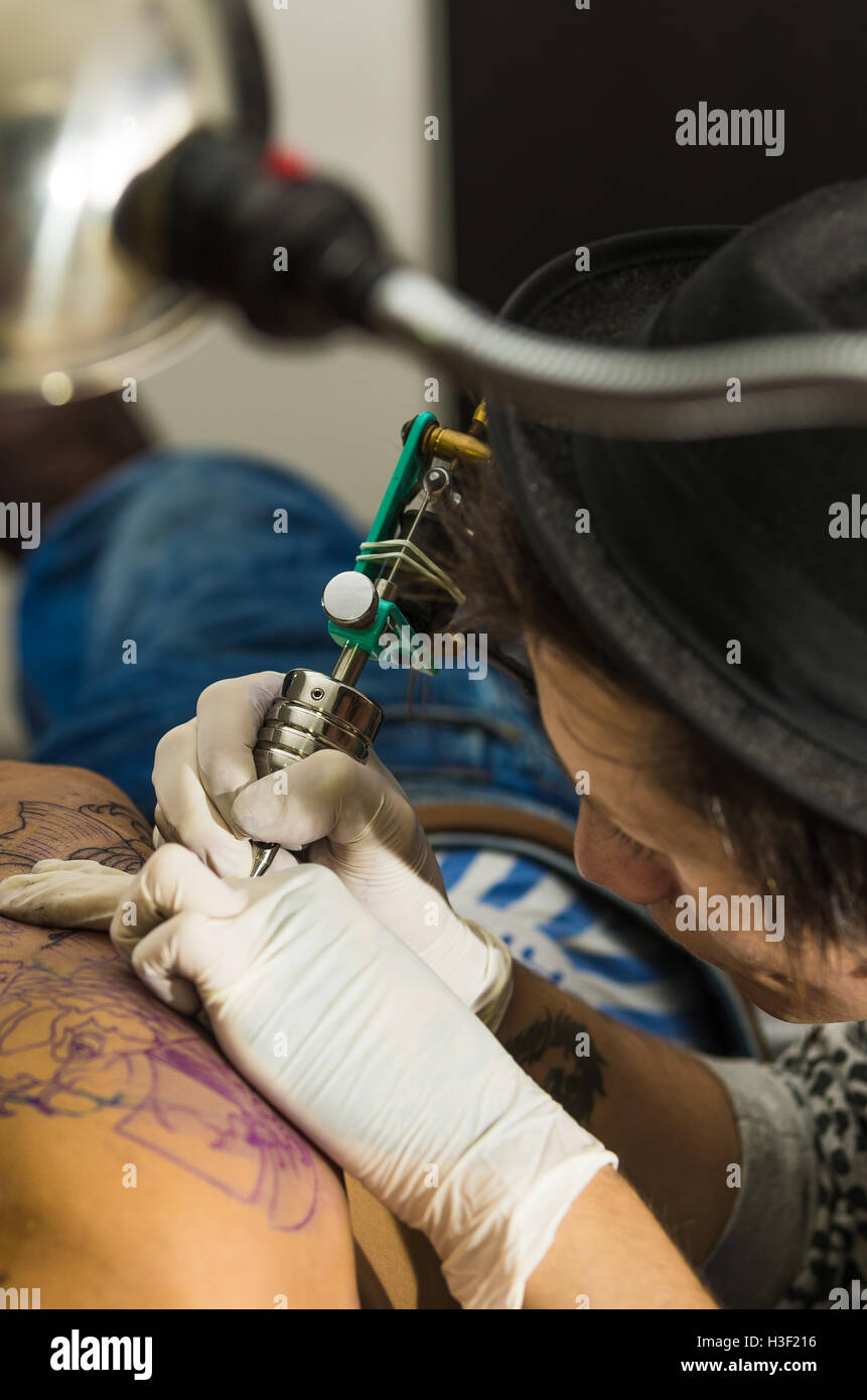 Tattoo artist working Stock Photo - Alamy