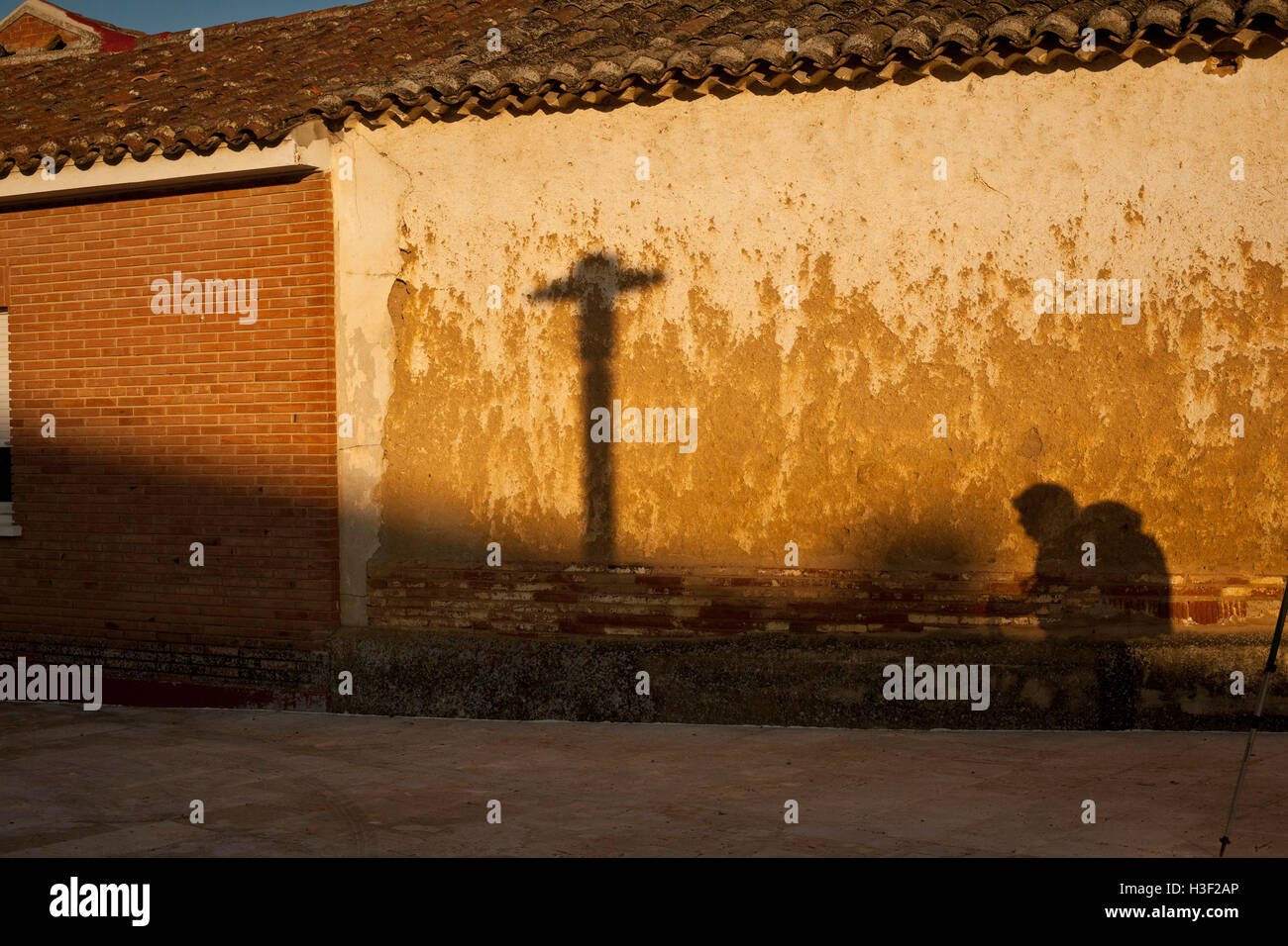 Shadow of a cross and a pilgrim on a village wall along the Camino de ...