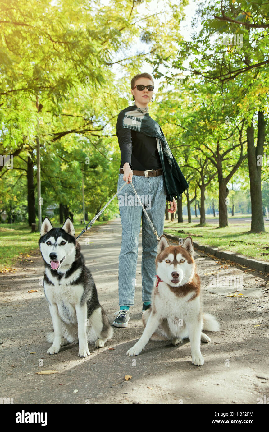 Young girl with two dogs Husky walking through the park Stock Photo - Alamy