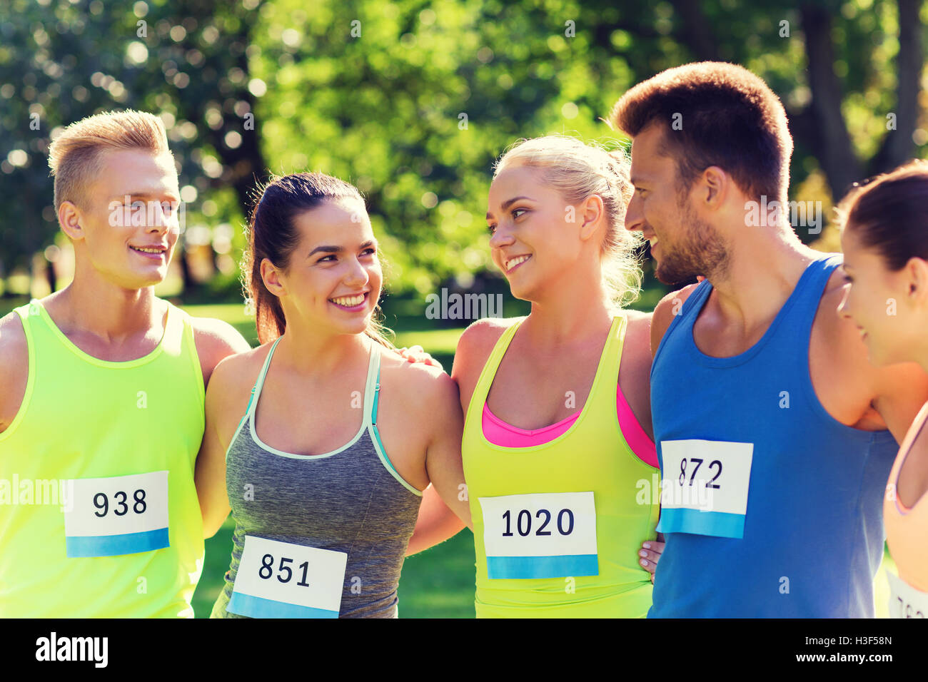 happy friends or couple with racing badge numbers Stock Photo - Alamy