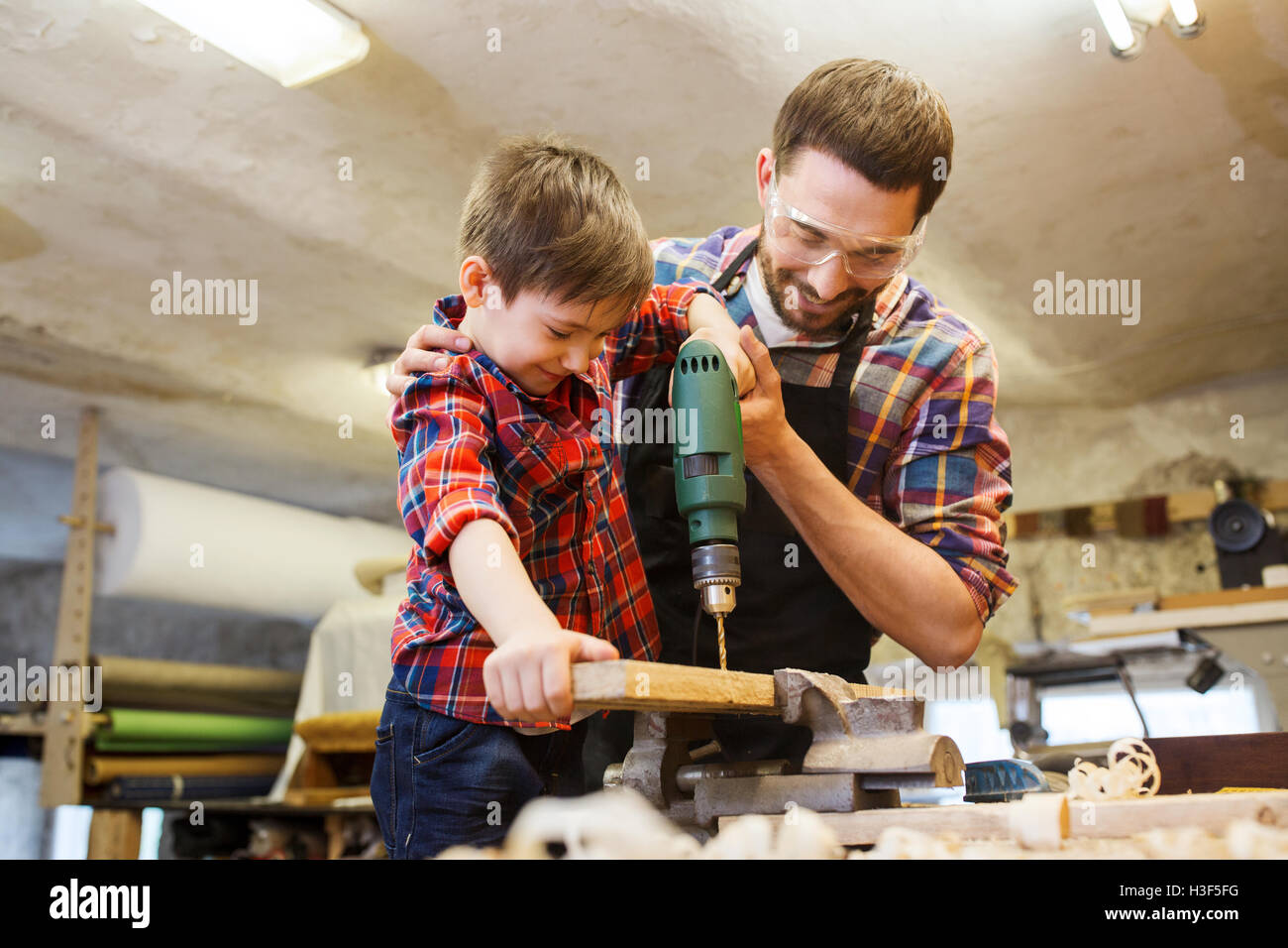 father and son with drill working at workshop Stock Photo - Alamy