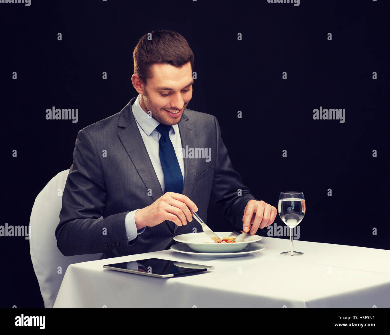 smiling man with tablet pc eating main course Stock Photo - Alamy