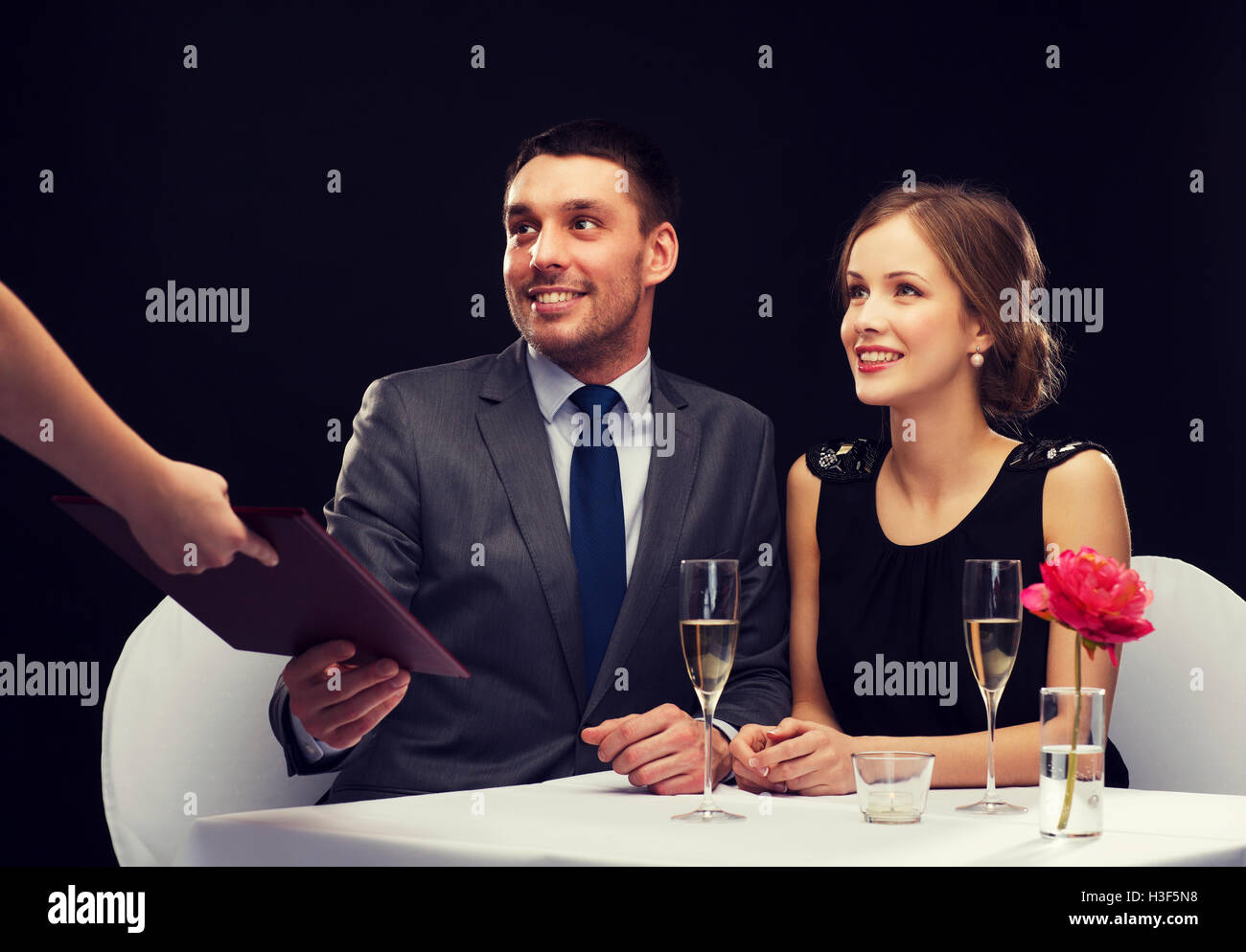 waiter giving menu to happy couple at restaurant Stock Photo - Alamy