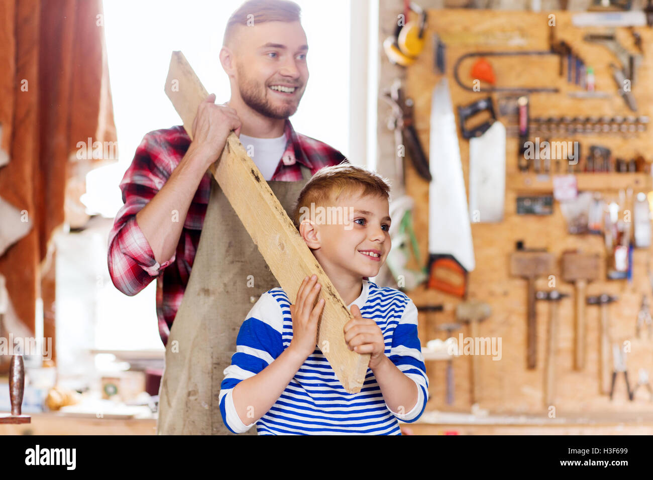 happy father and son with wood plank at workshop Stock Photo - Alamy