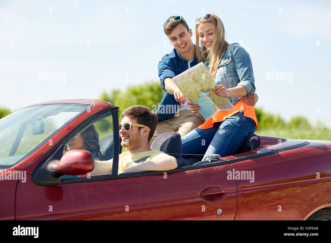 happy friends with map driving in cabriolet car Stock Photo - Alamy