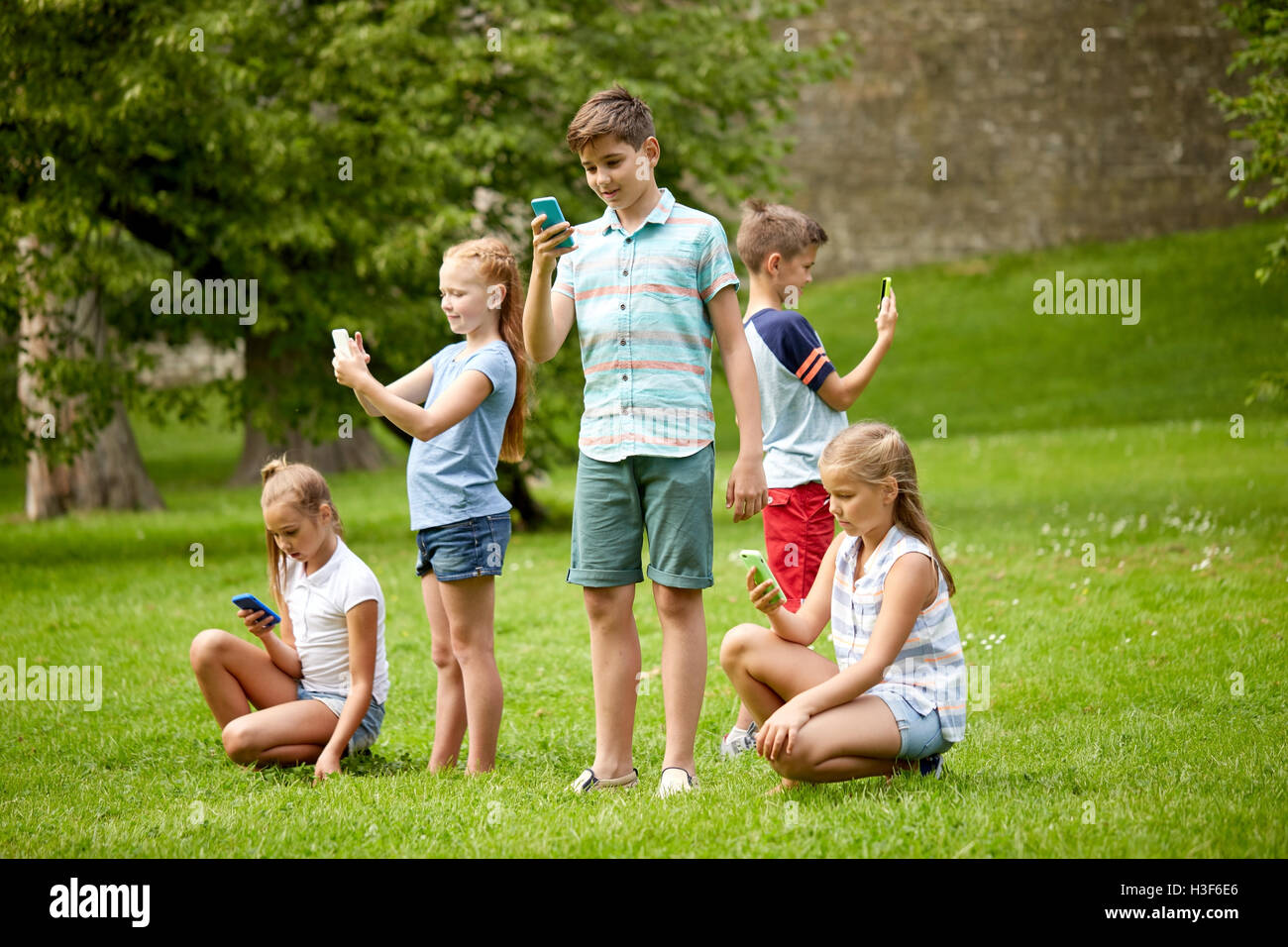 kids with smartphones playing game in summer park Stock Photo - Alamy