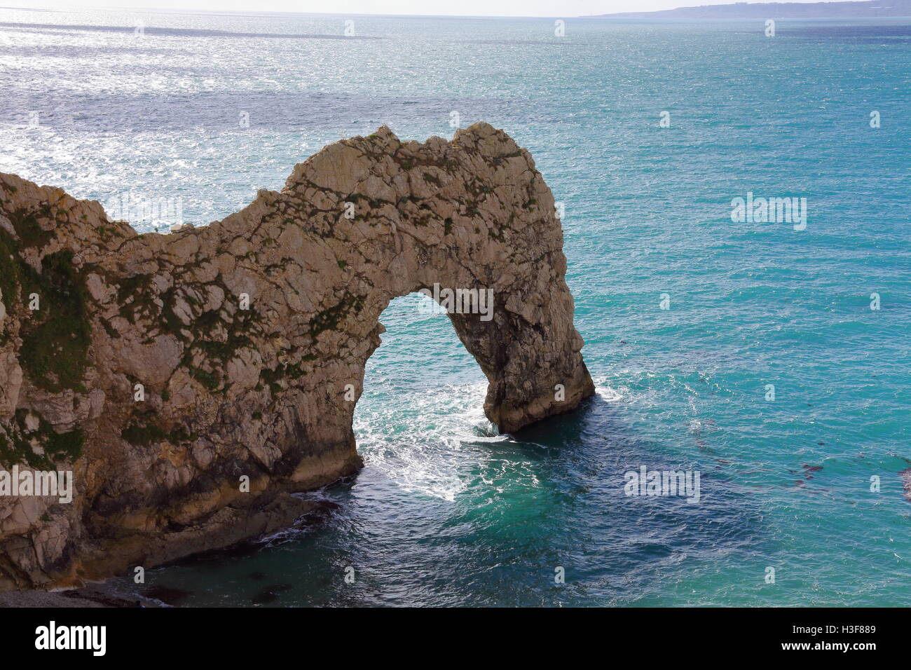 The hole in the rock at Durdle door with the blue water washing against ...