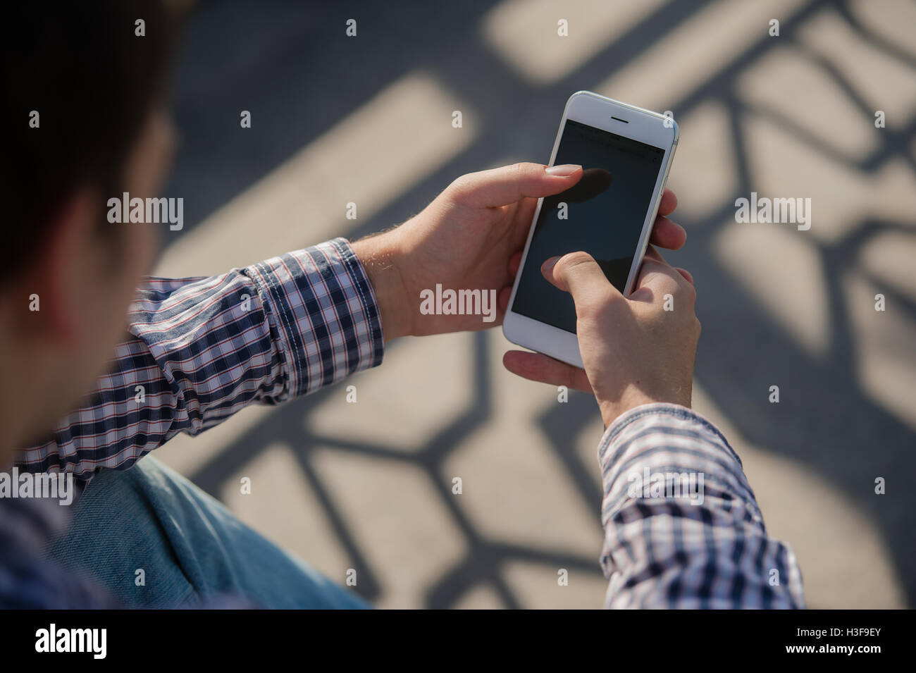 Man uses his Mobile smart Phone outdoor while sitting on a stairs ...